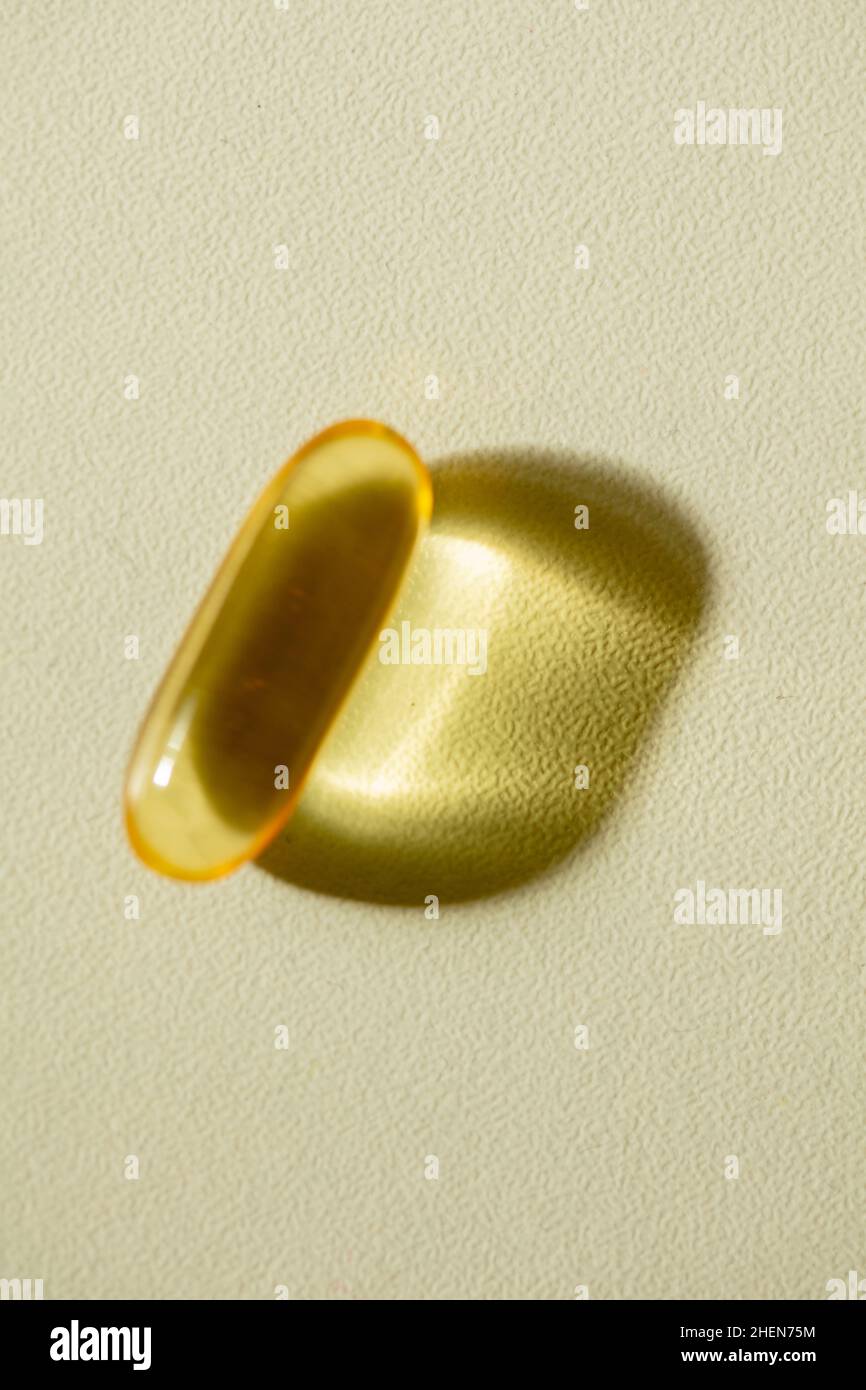 Very close-up medical still-life of Omega−3 capsule on plain background ...