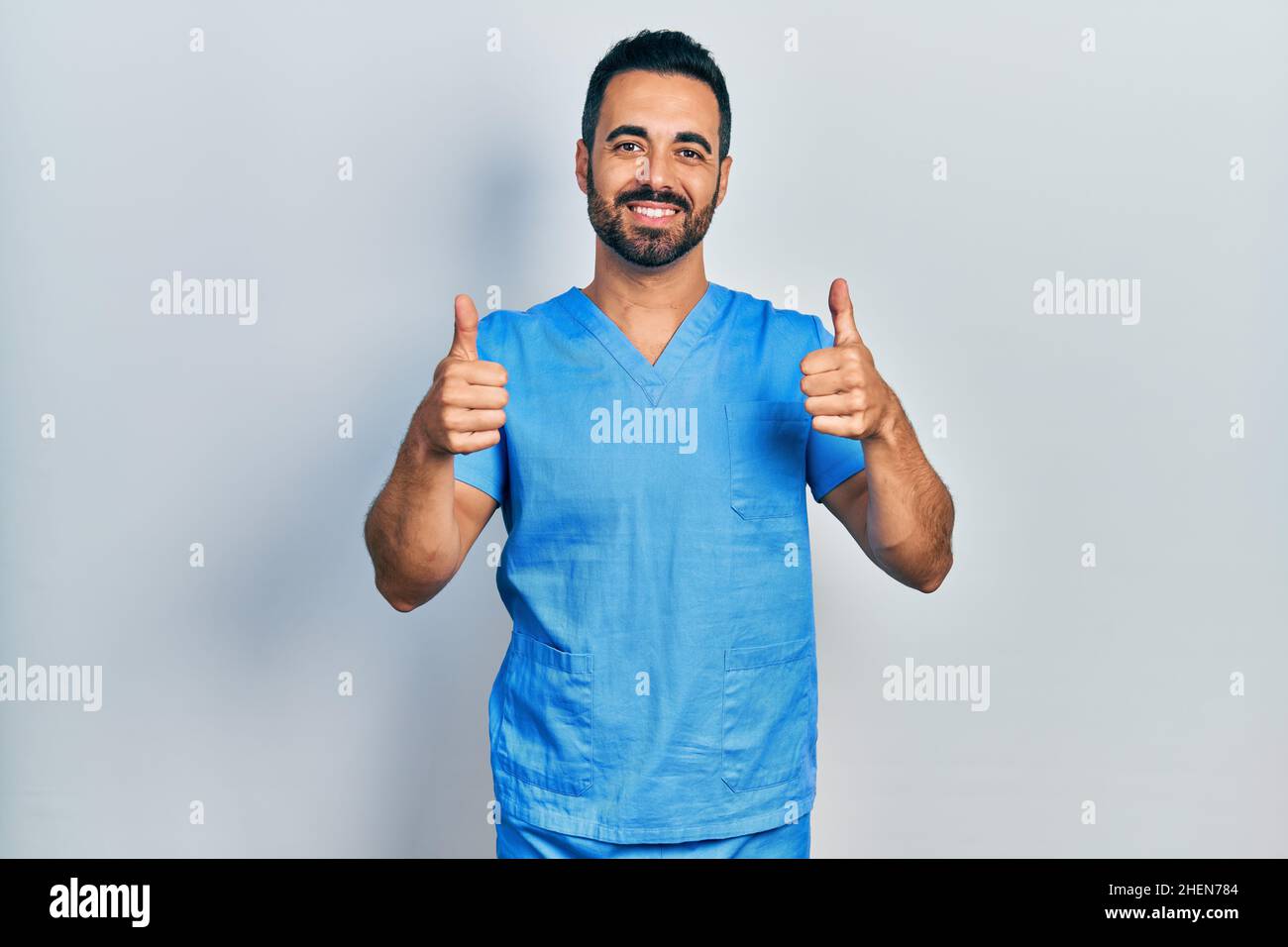 Handsome hispanic man with beard wearing blue male nurse uniform ...