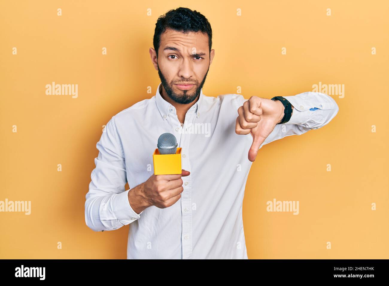 Hispanic man with beard holding reporter microphone with angry face ...