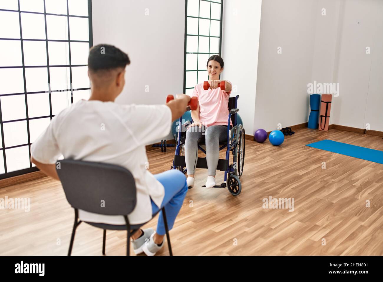 Young disabled woman sitting on wheelchair making mobility exercise ...