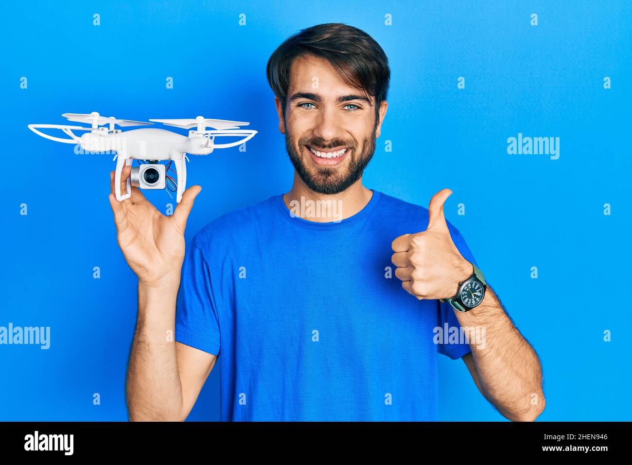 Young hispanic man holding drone smiling happy and positive, thumb up ...