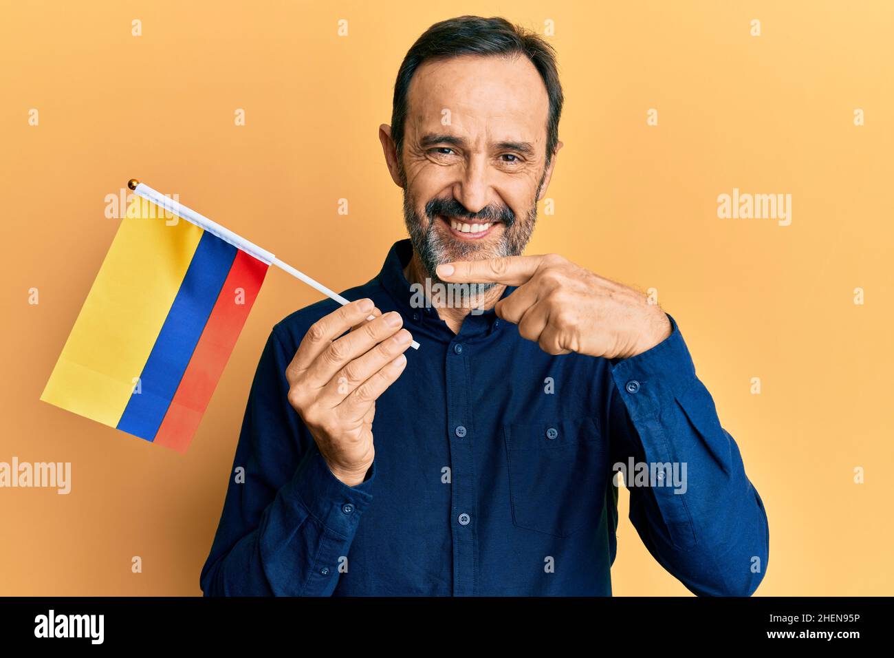 Middle age hispanic man holding colombia flag smiling happy pointing ...