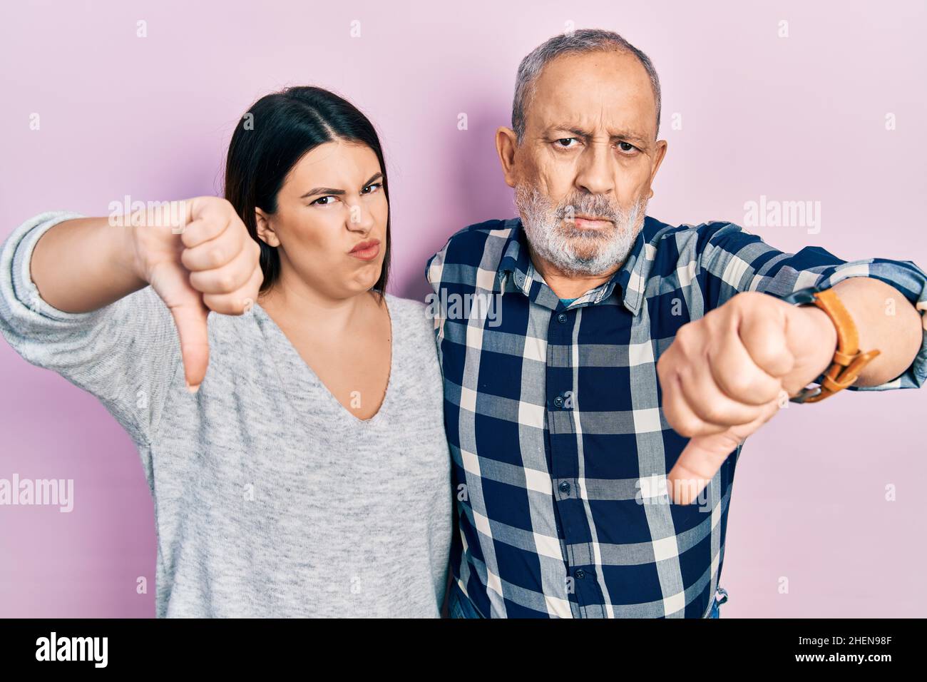 Hispanic father and daughter wearing casual clothes looking unhappy and ...