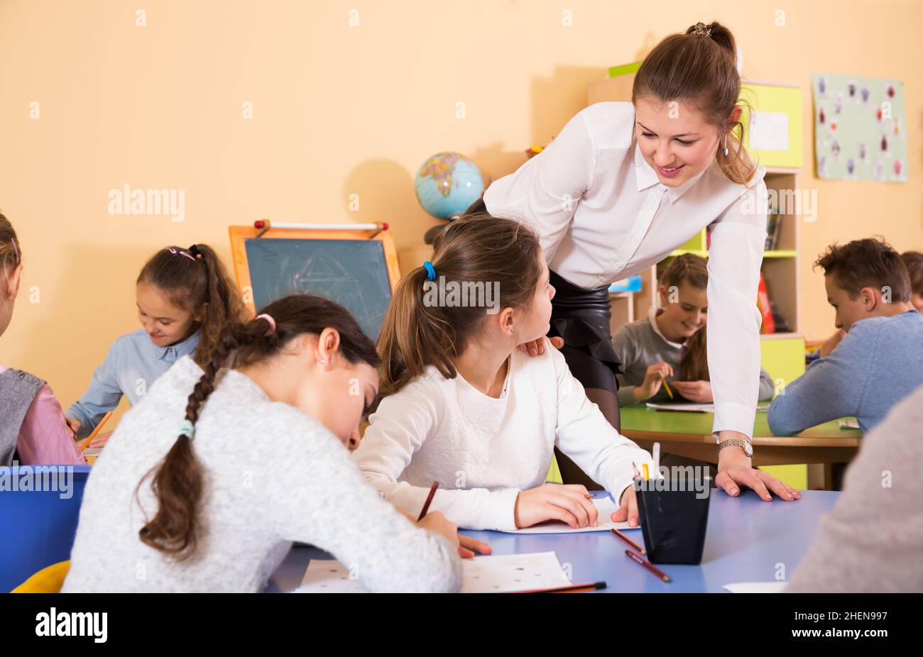Teacher helping children drawing Stock Photo - Alamy