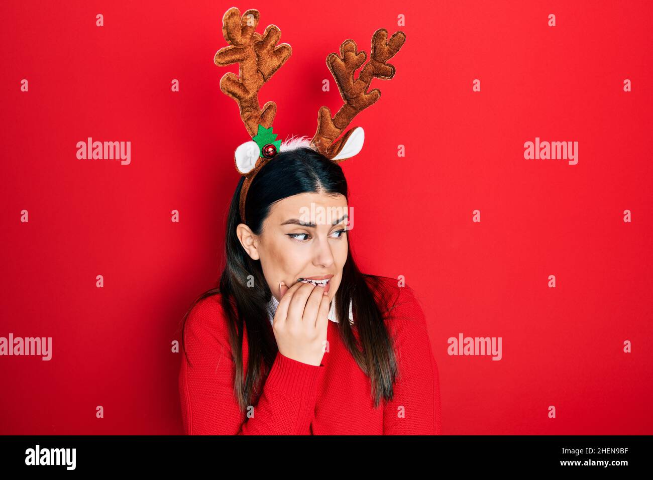 Young hispanic woman wearing cute christmas reindeer horns looking ...