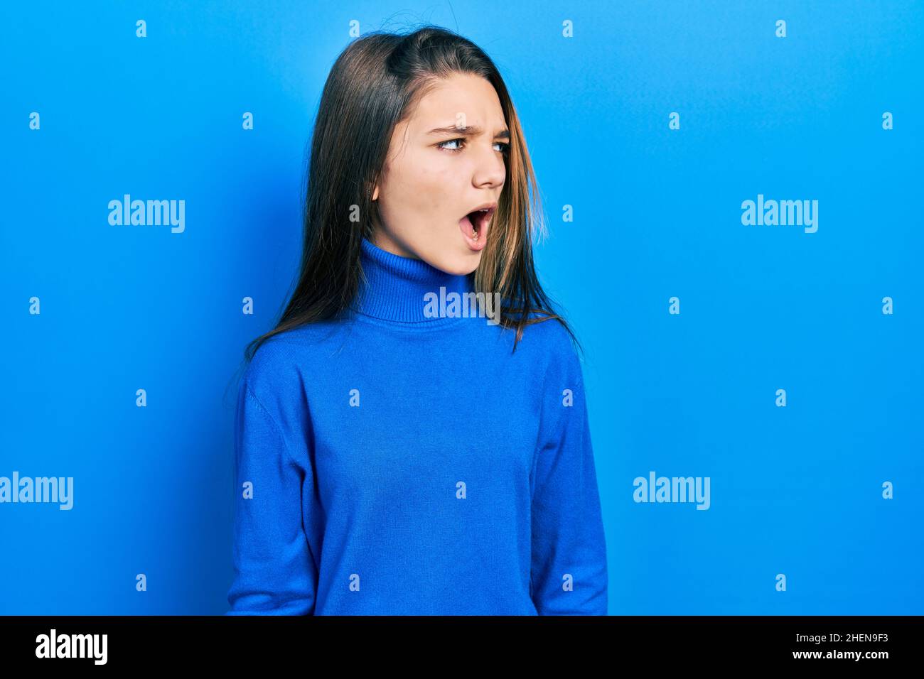 Young brunette girl wearing turtleneck sweater angry and mad screaming ...