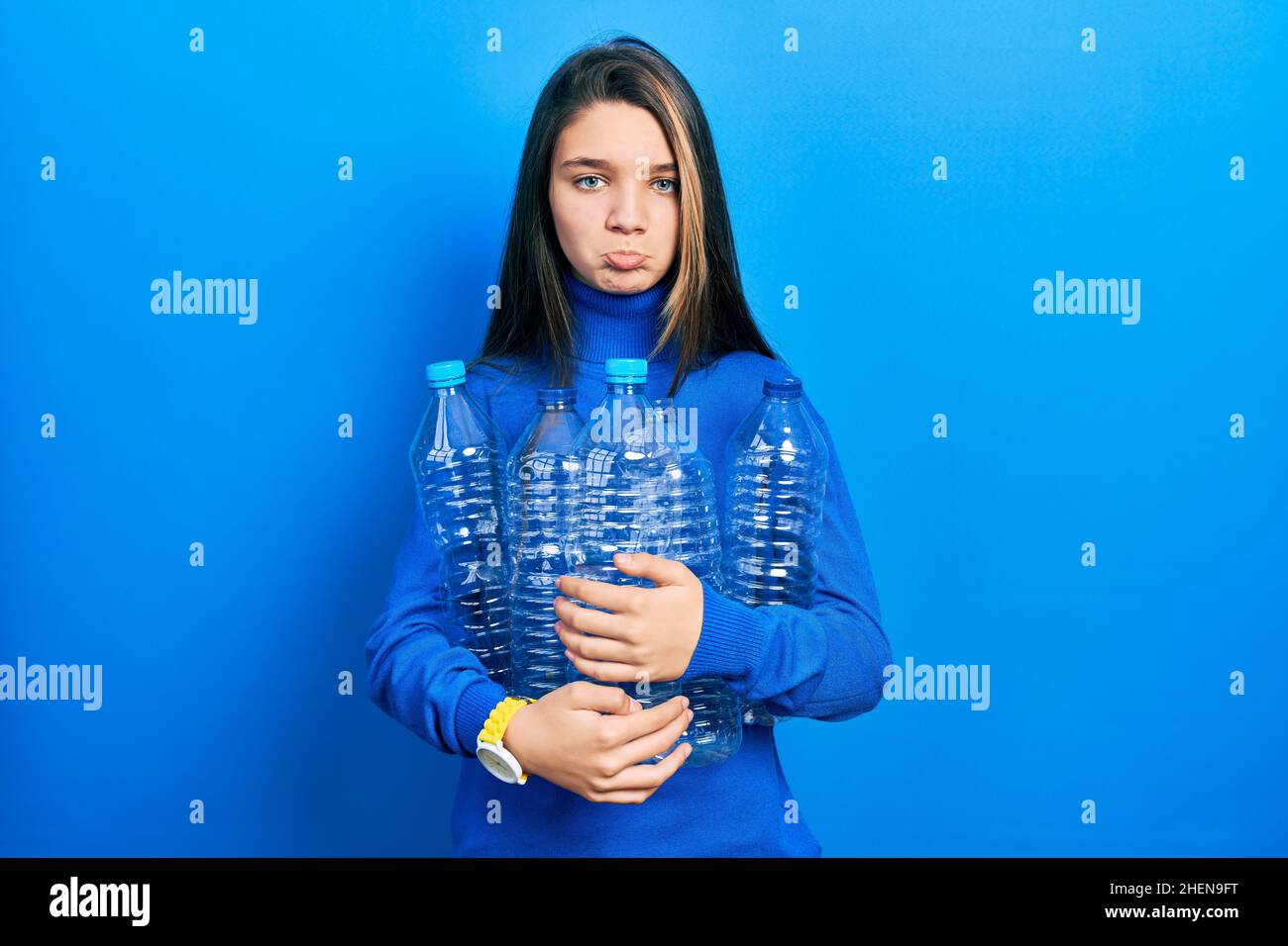 Young brunette girl holding recycling plastic bottles depressed and ...