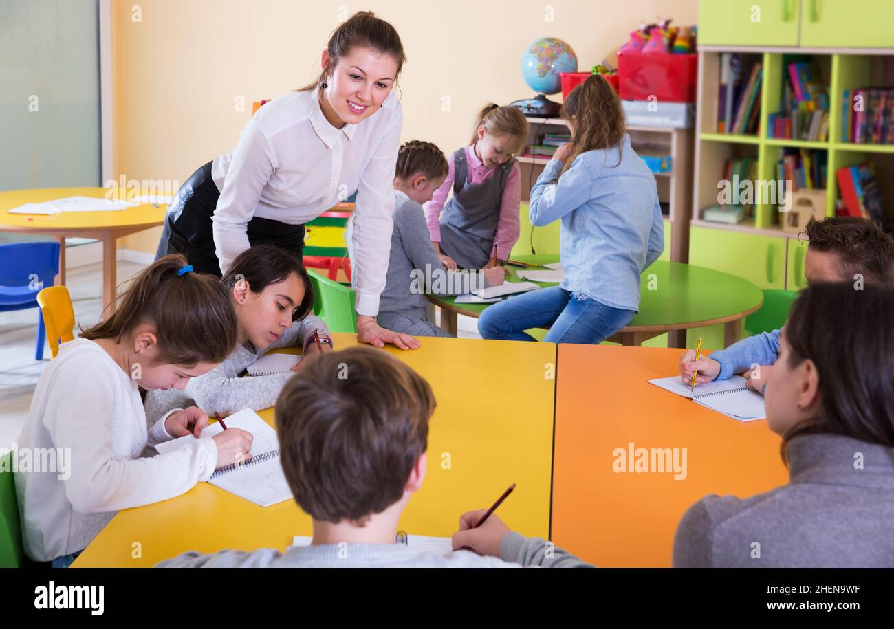 Teacher helping children drawing Stock Photo - Alamy