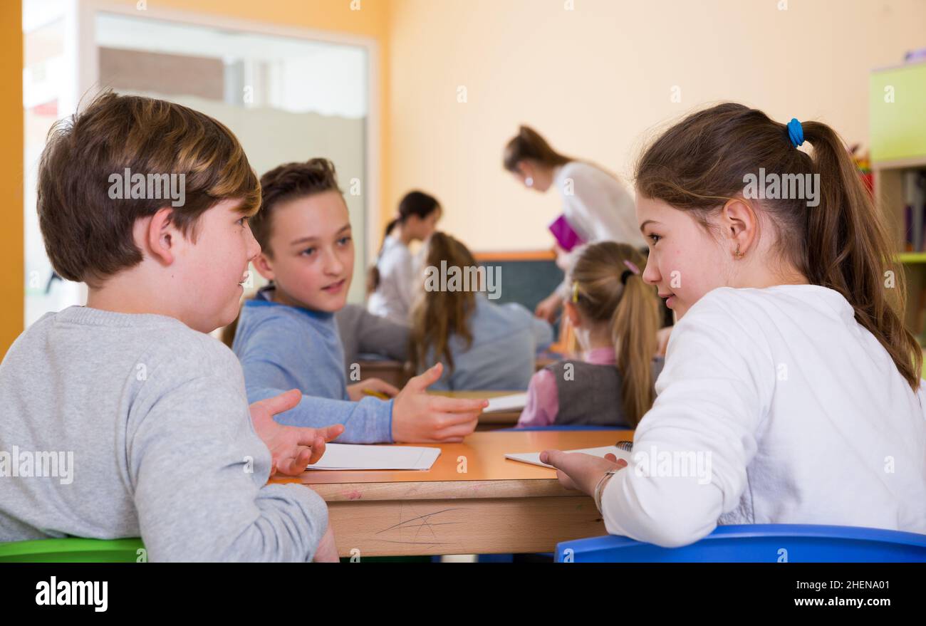 Schoolchildren chatting during lesson Stock Photo - Alamy