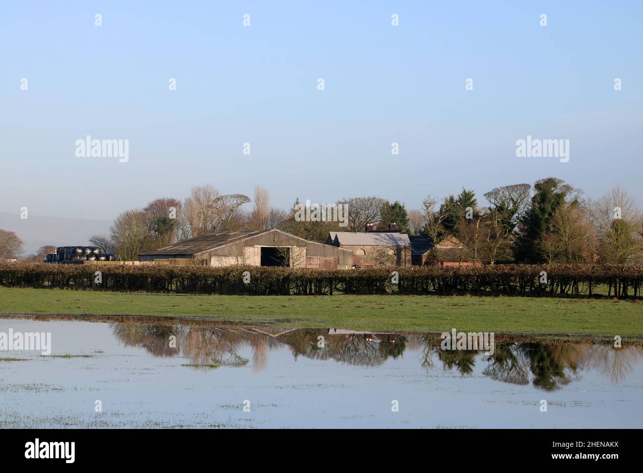 View of a set of farm buildings and their reflection in water in a ...