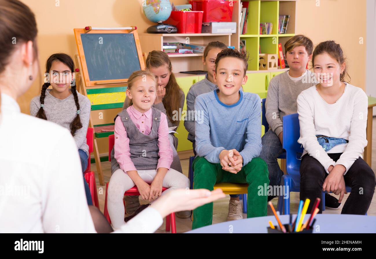 Positive boys and girls listening teacher Stock Photo - Alamy