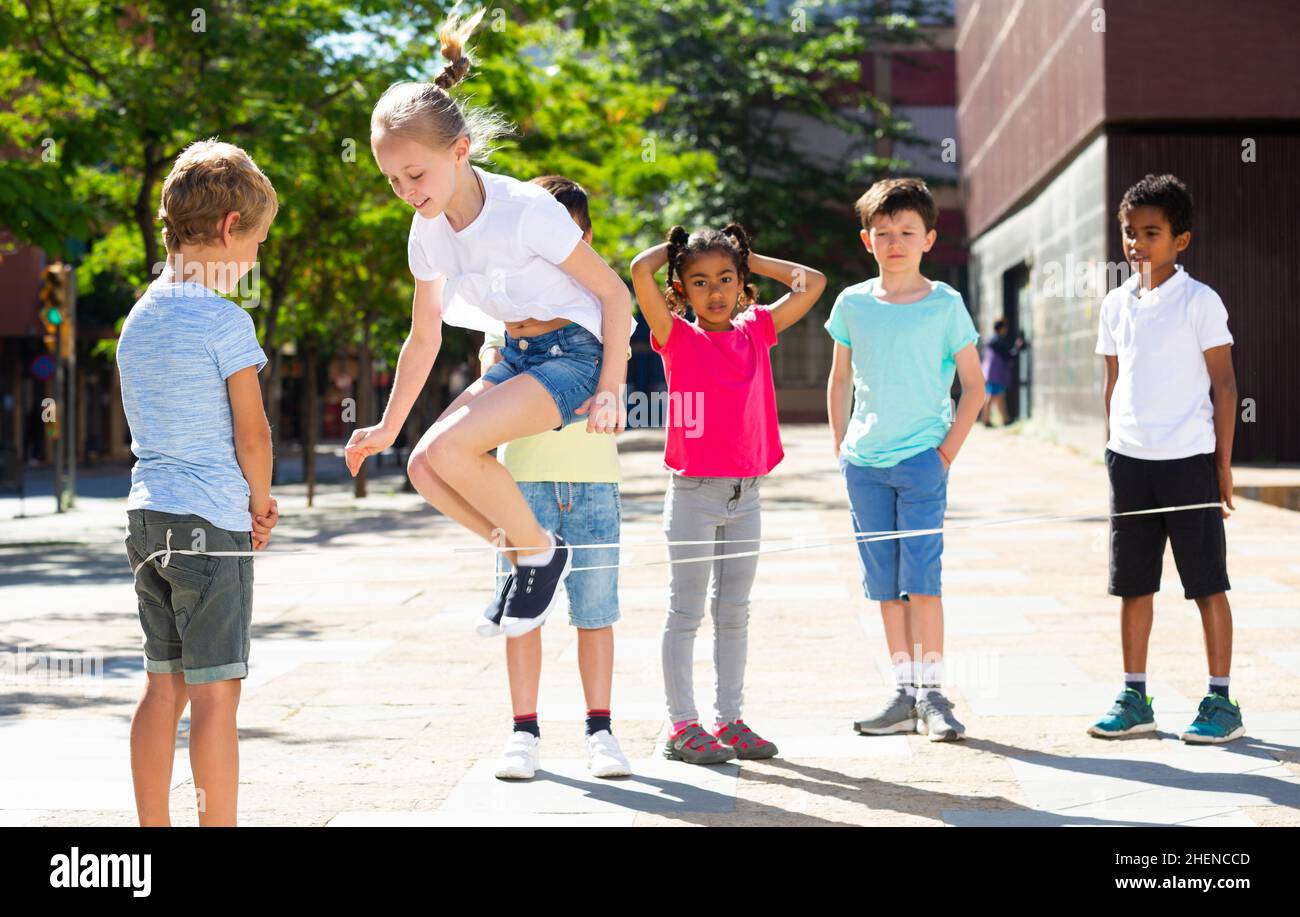Happy smiling little friends playing with chinese jumping rope at ...