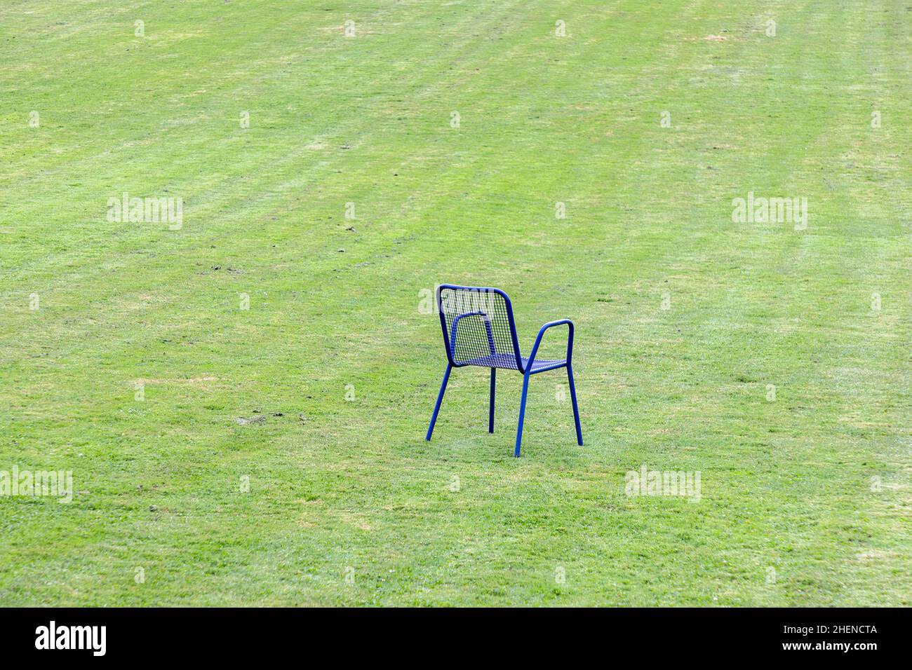 empty blue chiar at a green meadow symbolizing loneliness in corona ...