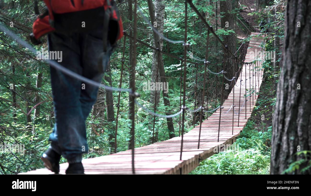 Man walking on a hanging bridge in National Park, USA. Rear view of a ...