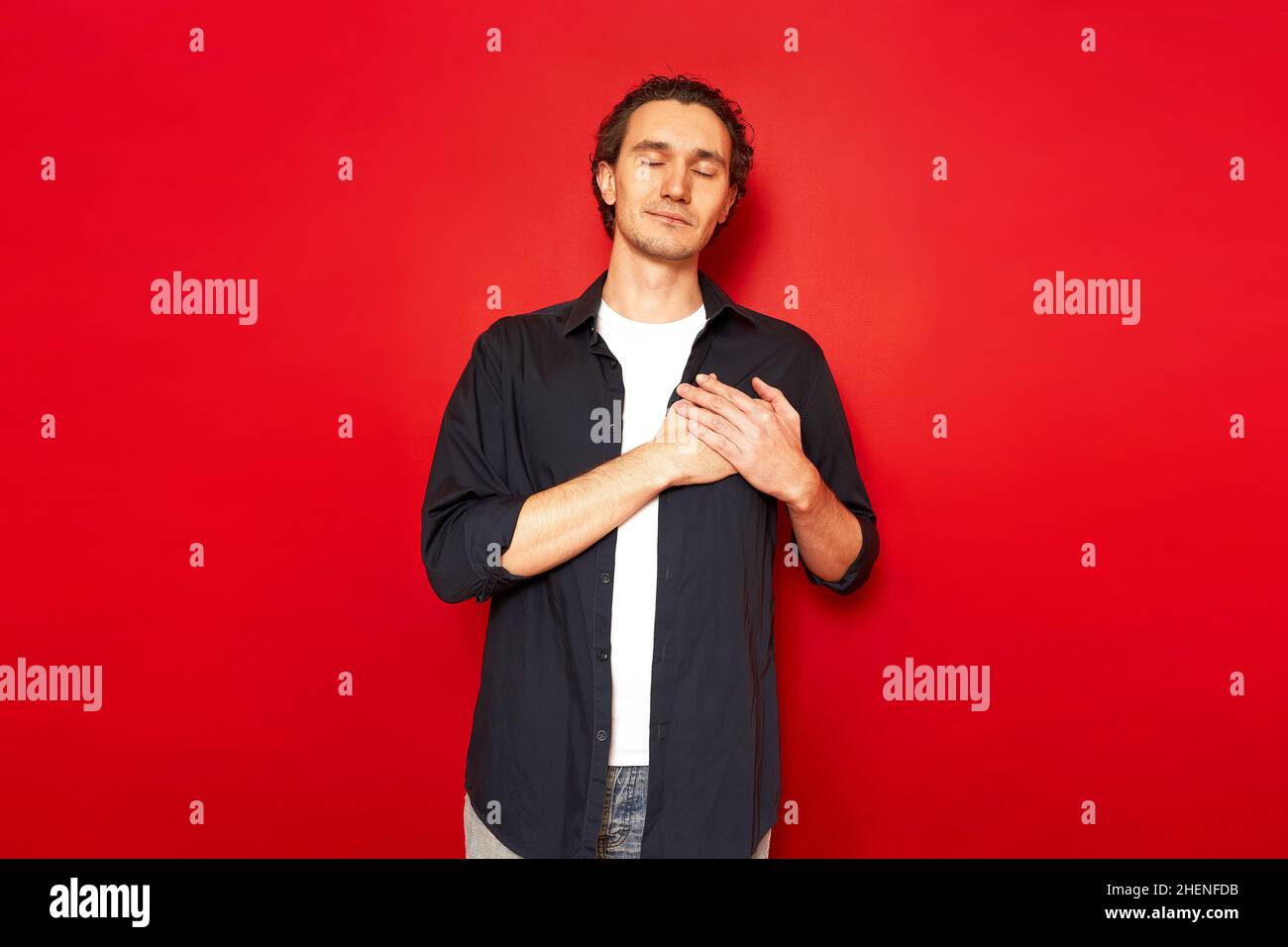 man with eyes closed holds both hands on chest showing heart pain ...