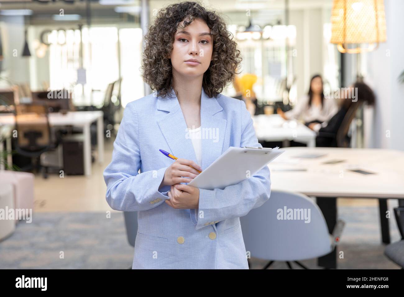 Pretty business woman wearing formal clothes standing in the office and ...