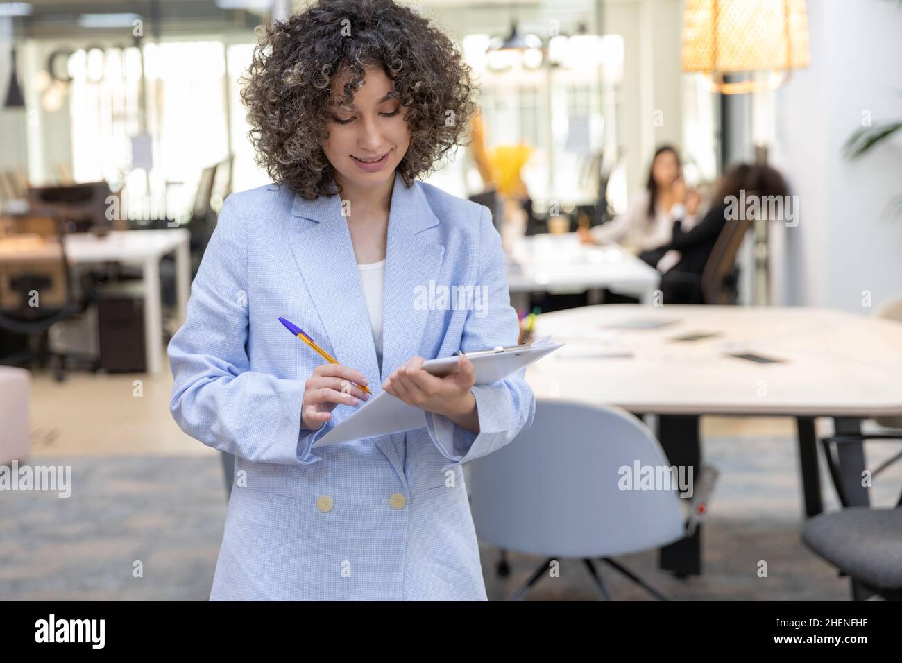 Pretty business woman wearing formal clothes standing in the office and ...