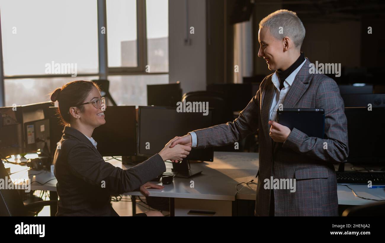 Two young business women shake hands at work. The office staff made a ...