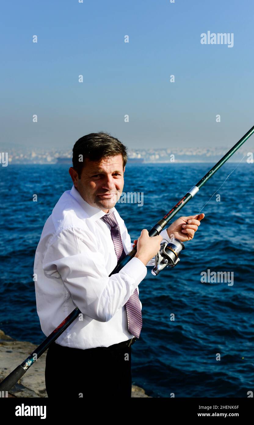 A Turkish man fishing from the waterfront along the Golden horn in ...