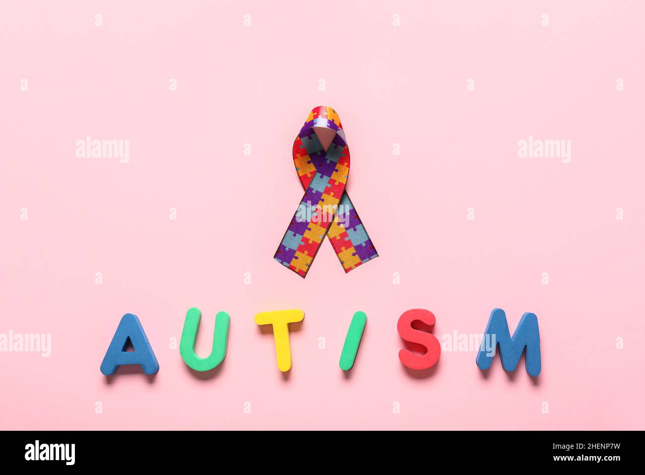 Word AUTISM with awareness ribbon on pink background Stock Photo - Alamy