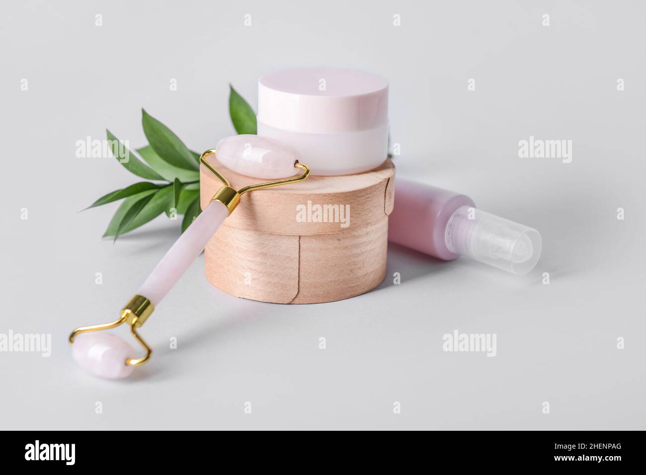 Face massage roller with cosmetic products on light background Stock ...