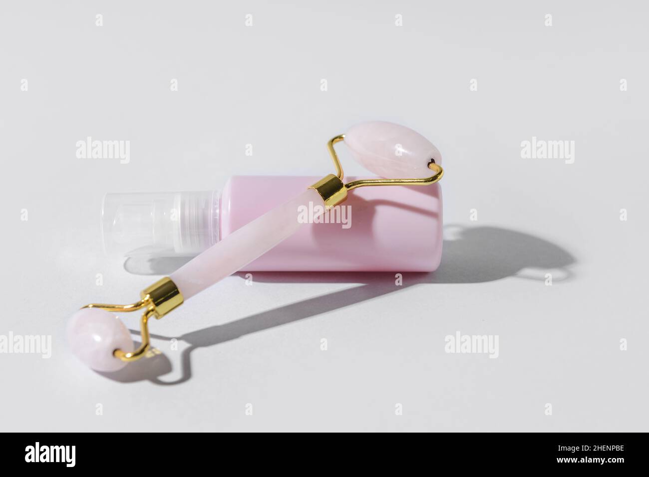 Face massage roller with cosmetic product on light background Stock ...