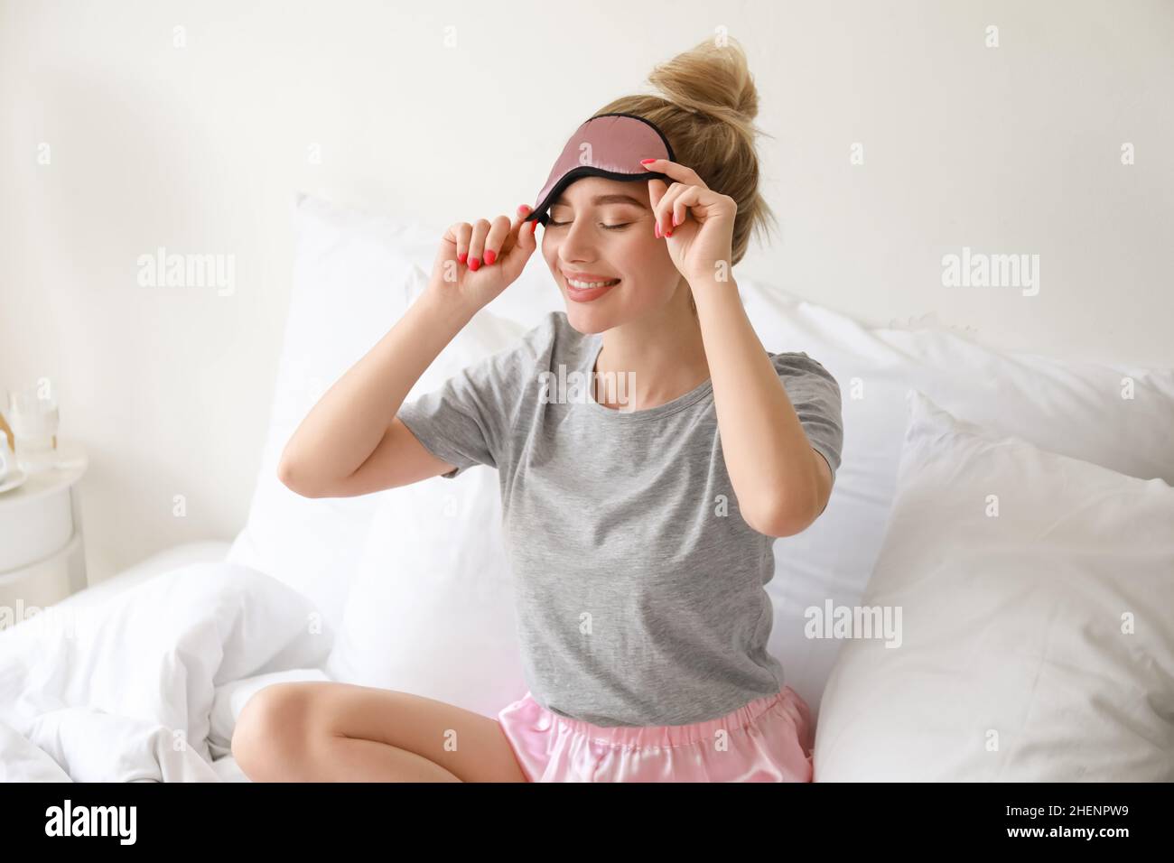 Beautiful young woman taking off sleeping mask in bedroom Stock Photo ...