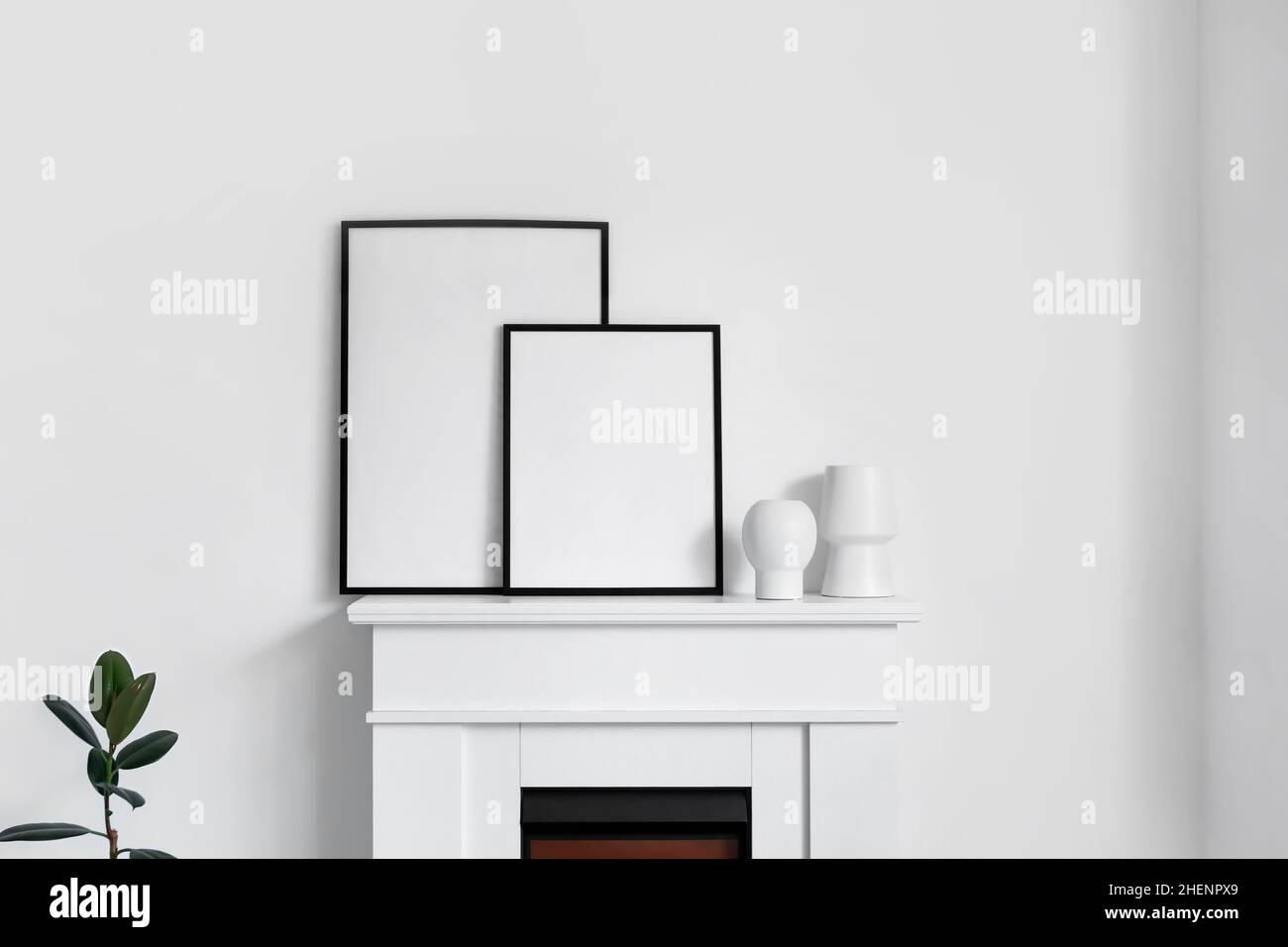 Fireplace with blank poster frames in light bedroom Stock Photo - Alamy