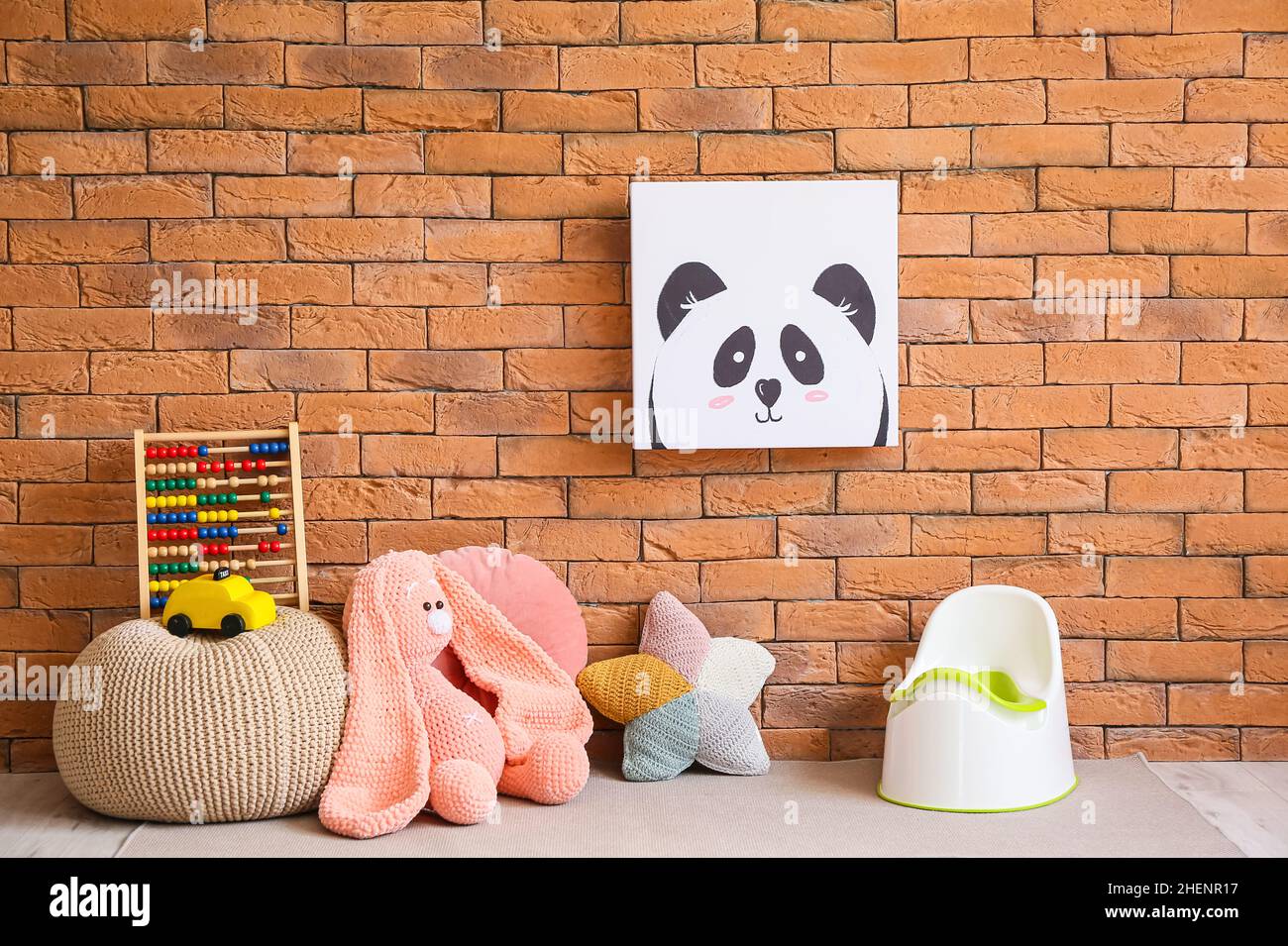 White potty, toys on floor and painting on brick wall in room Stock ...