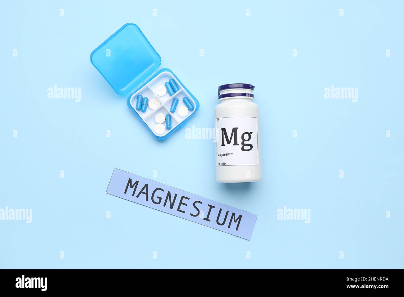 Plastic container with pills, bottle and word MAGNESIUM on color ...