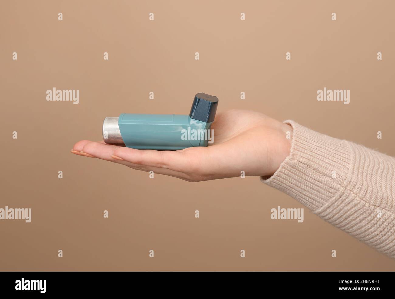 Woman holding asthma inhaler on brown background Stock Photo - Alamy