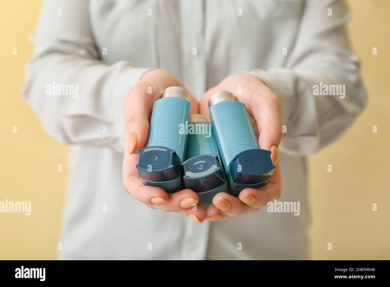 Woman holding asthma inhaler on beige background Stock Photo - Alamy