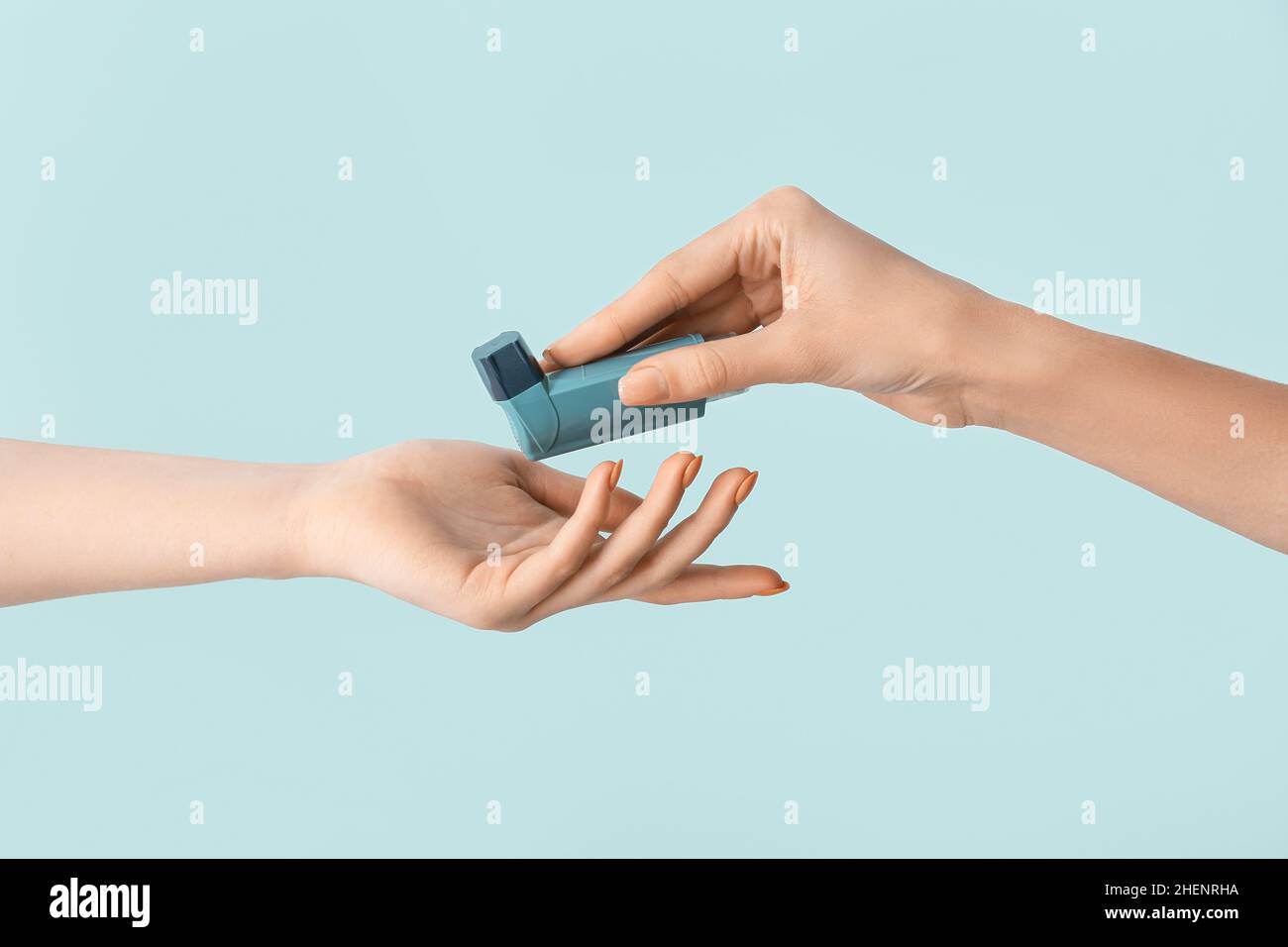 Female hands with asthma inhaler on blue background Stock Photo - Alamy