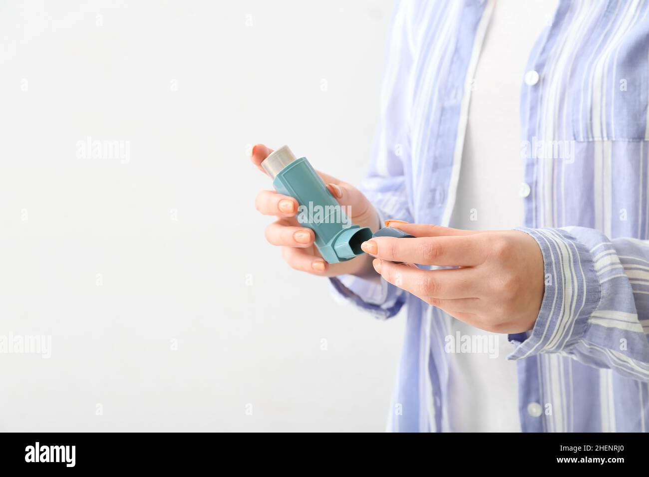 Woman holding asthma inhalers on light background Stock Photo - Alamy