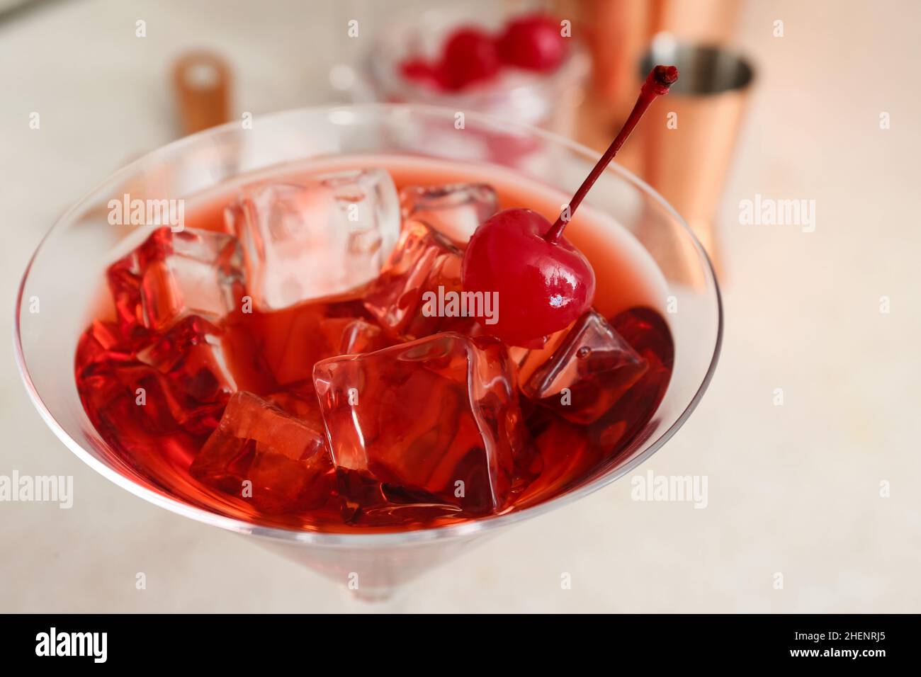Glass of iced Manhattan cocktail with cherry on light background ...