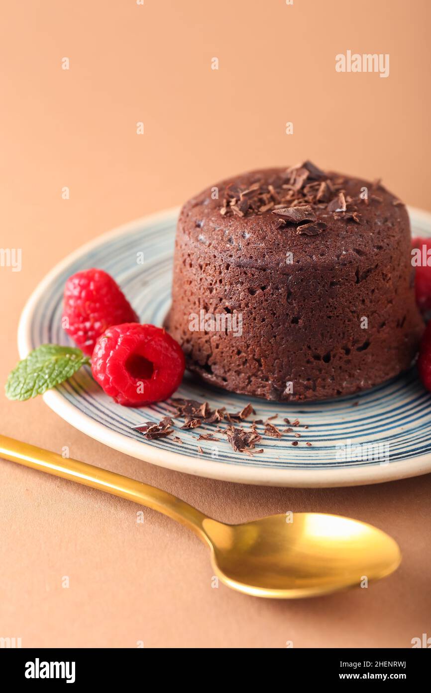 Plate with tasty lava cake fondant and raspberry on color background ...