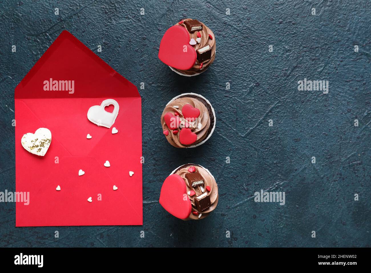 Tasty chocolate cupcakes for Valentine's Day and envelope on black ...