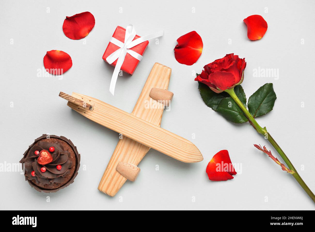 Wooden airplane, gift, rose and muffin on light background. Valentine's ...