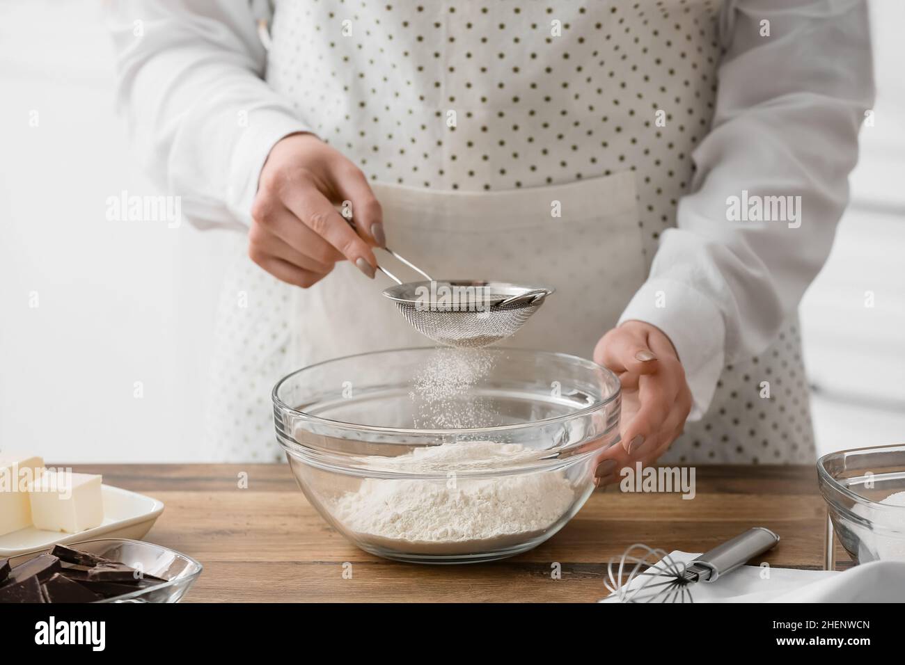 Woman adding flour into bowl for preparing chocolate brownie at table ...