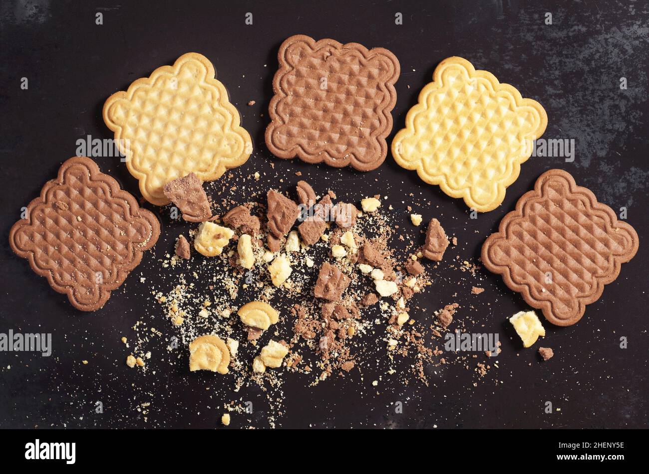 Chocolate and vanilla square cookies whole and broken on old black ...