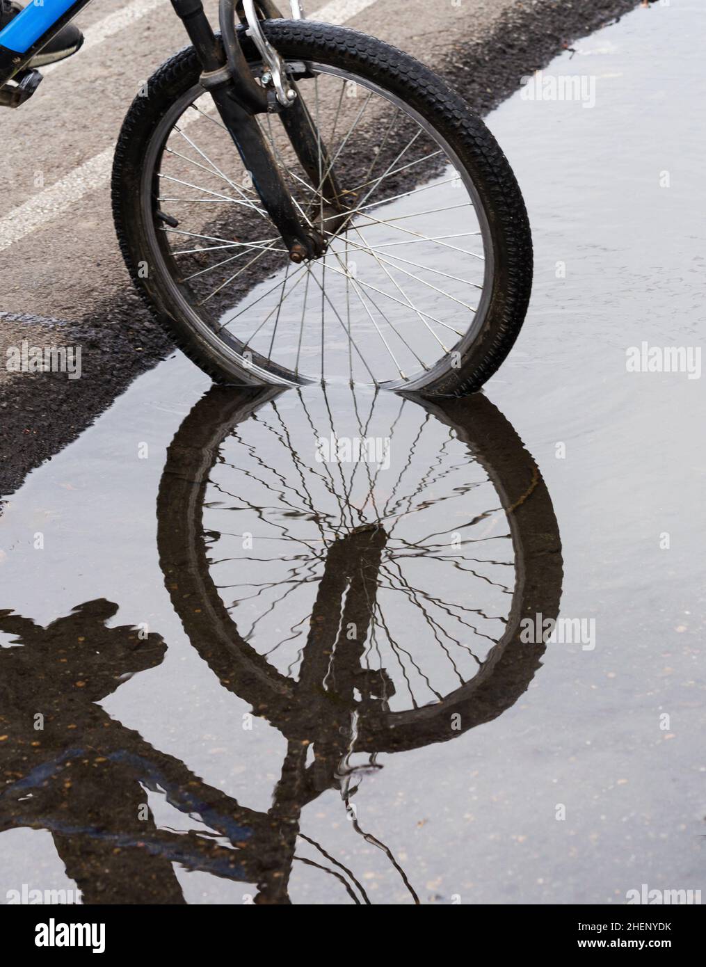 Reflection silhouette of a bike wheel with spokes in a spring rain ...