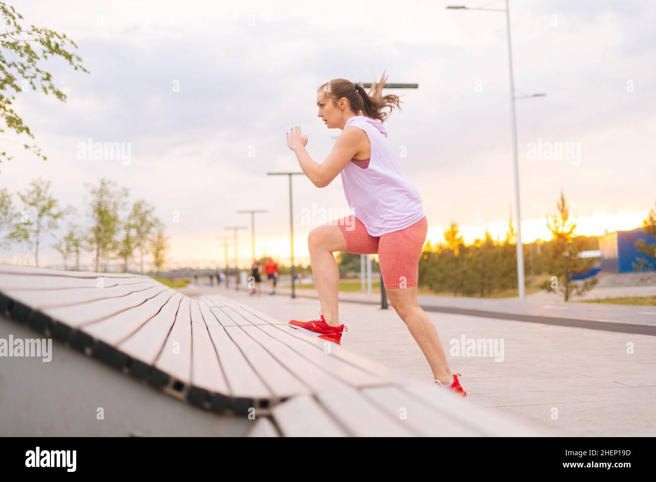 Side view of young Caucasian fit active woman doing stepping on bench ...