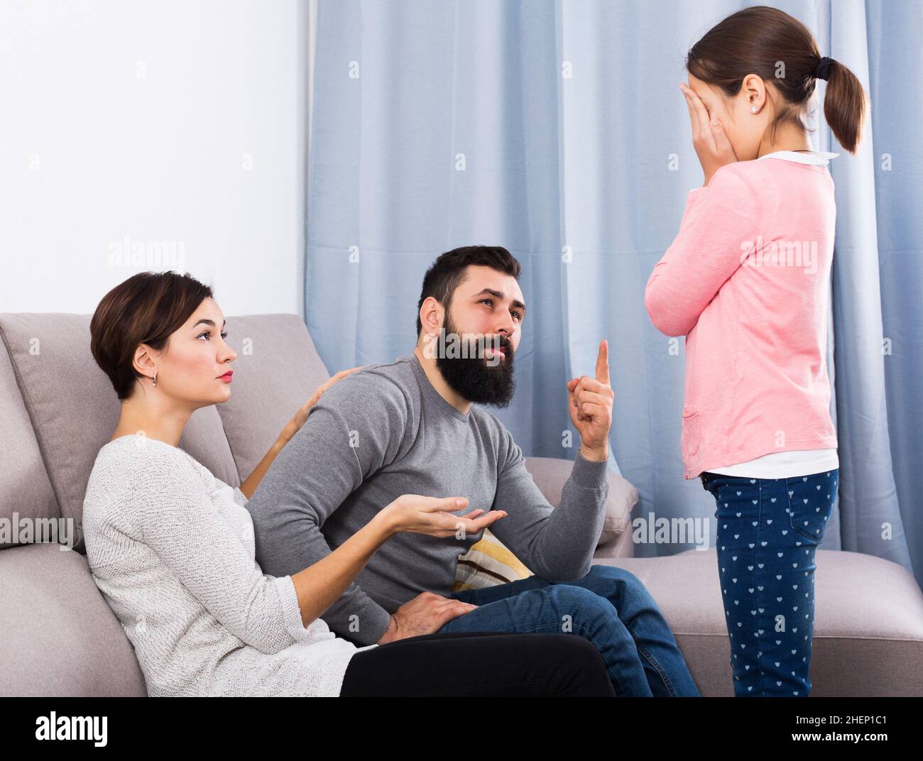 Father and mother correcting their child Stock Photo - Alamy
