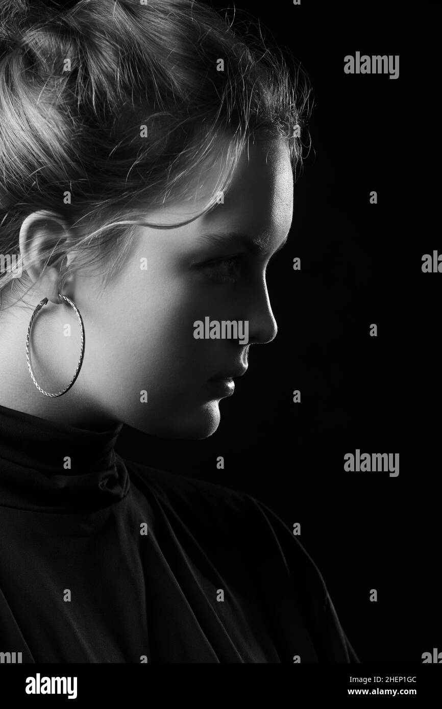 serious sad young woman with down syndrome on black background side ...