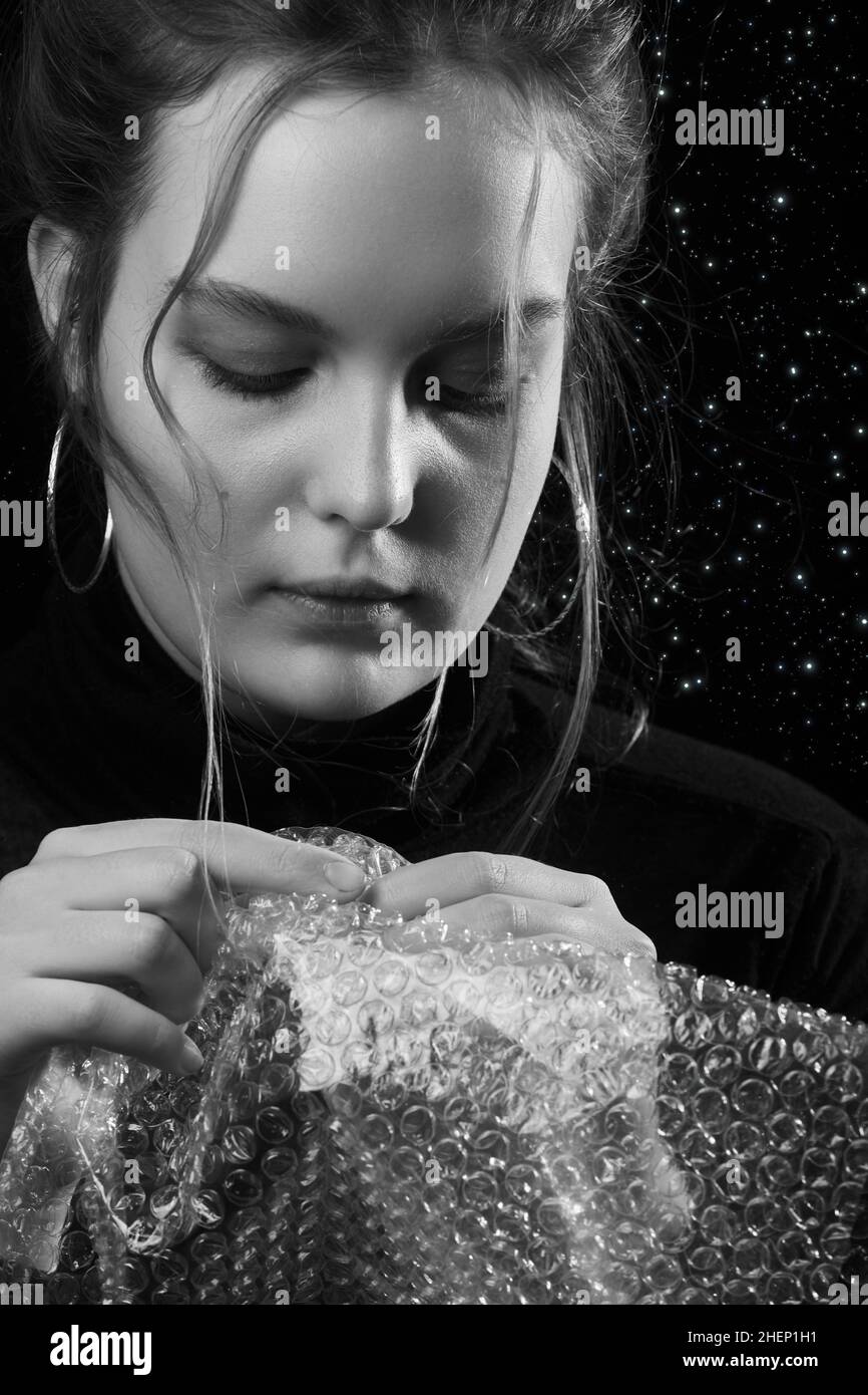 stressed woman in depression bursts bubbles of packaging cellophane ...
