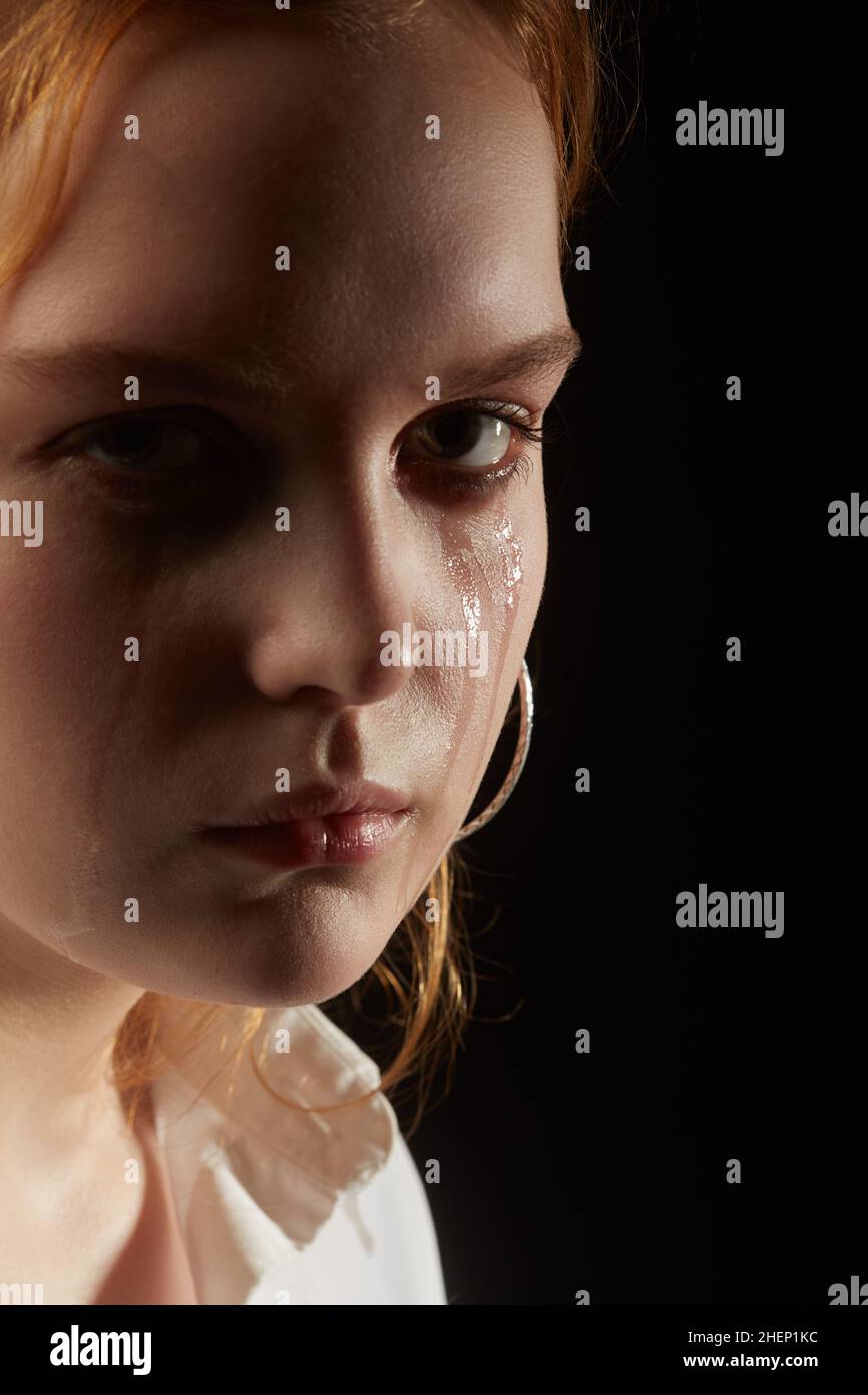 sad woman crying, looking at camera on black background, closeup ...