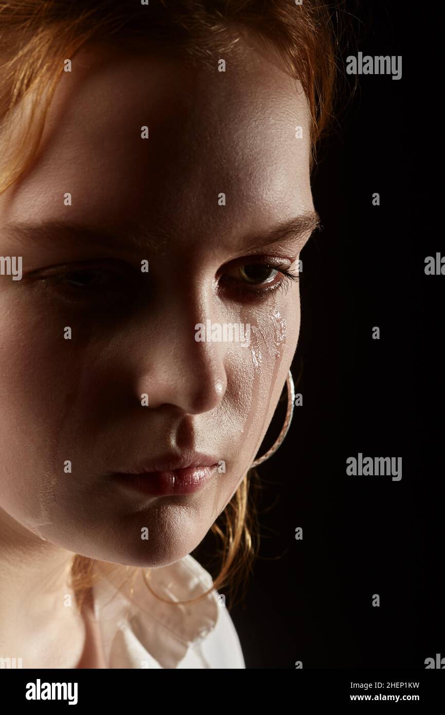 sad woman crying, looking aside on black background, closeup portrait ...