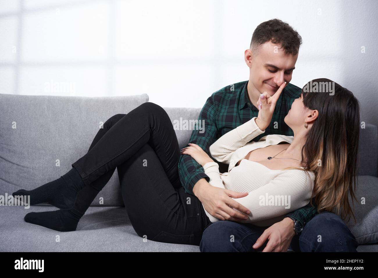 Happy attractive young couple sitting on sofa at home Stock Photo - Alamy