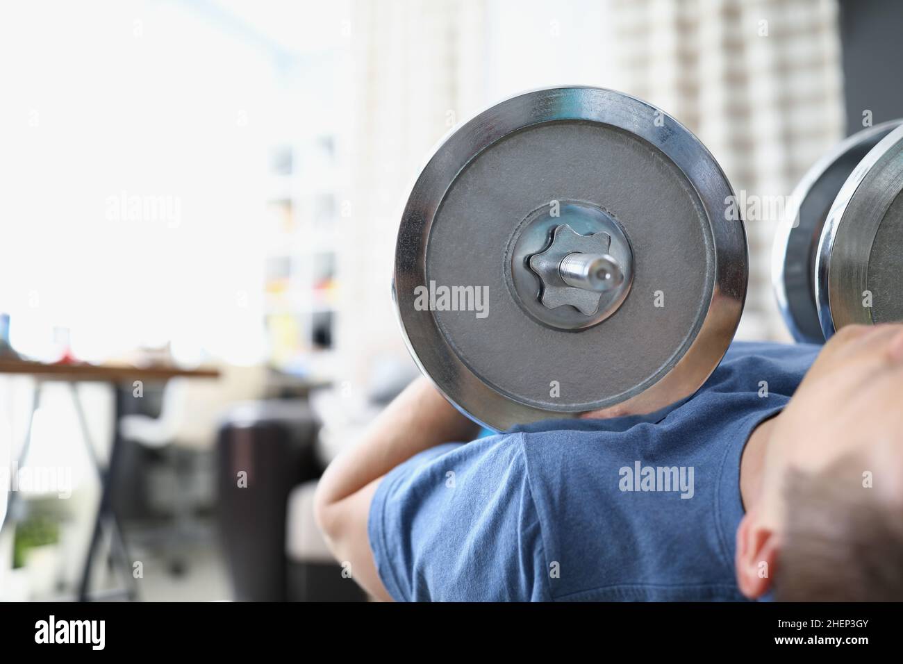 Man lift heavy metal dumbbell laying on training machine Stock Photo ...