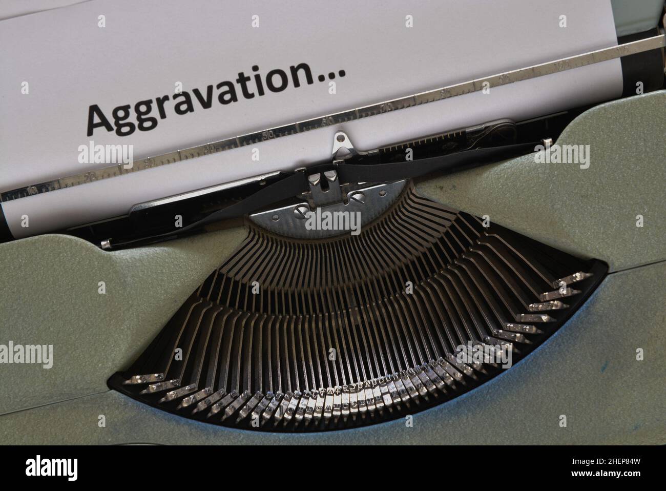 Aggravation - word typed on white paper held on typewriter platen ...